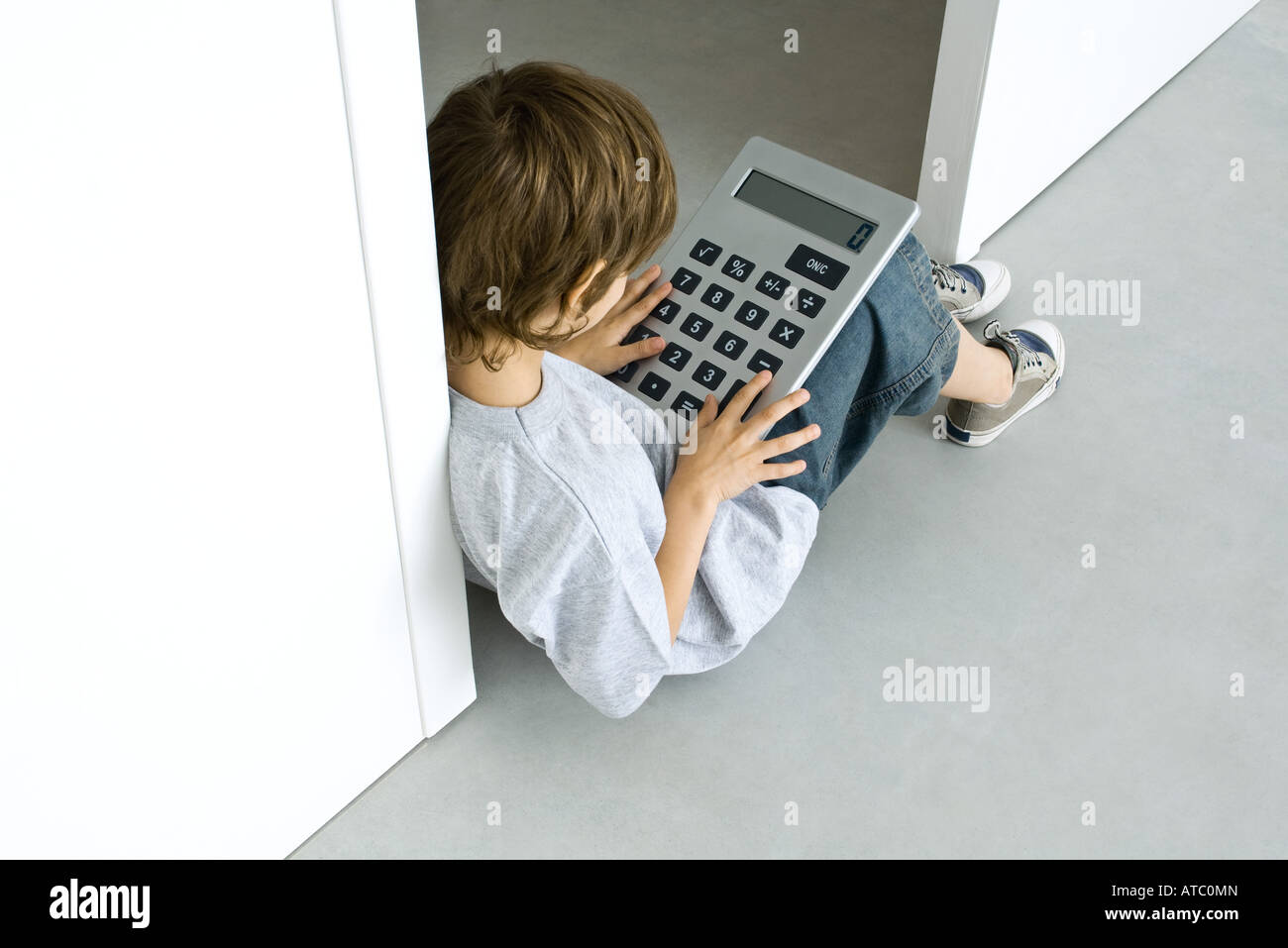 Little boy sitting on the ground, playing with large calculator, high ...