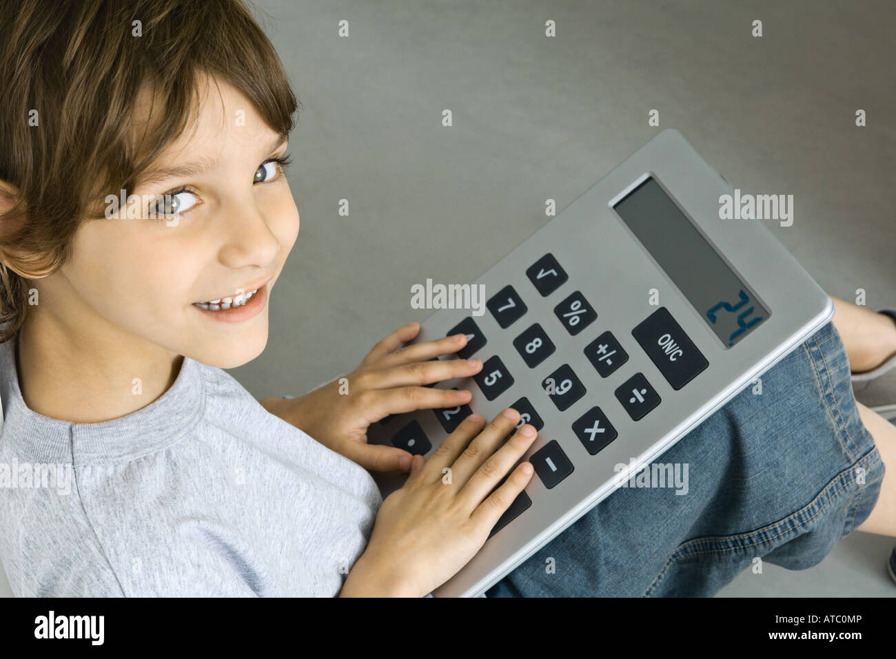 Little boy sitting on the ground, playing with large calculator ...