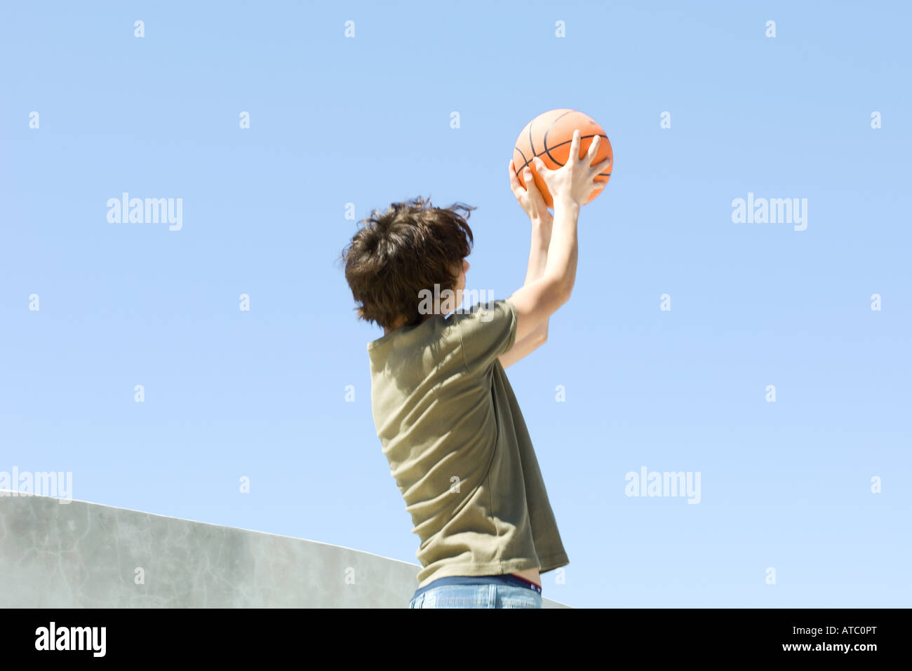 Teenage boy standing outdoors, throwing basketball, low angle view ...