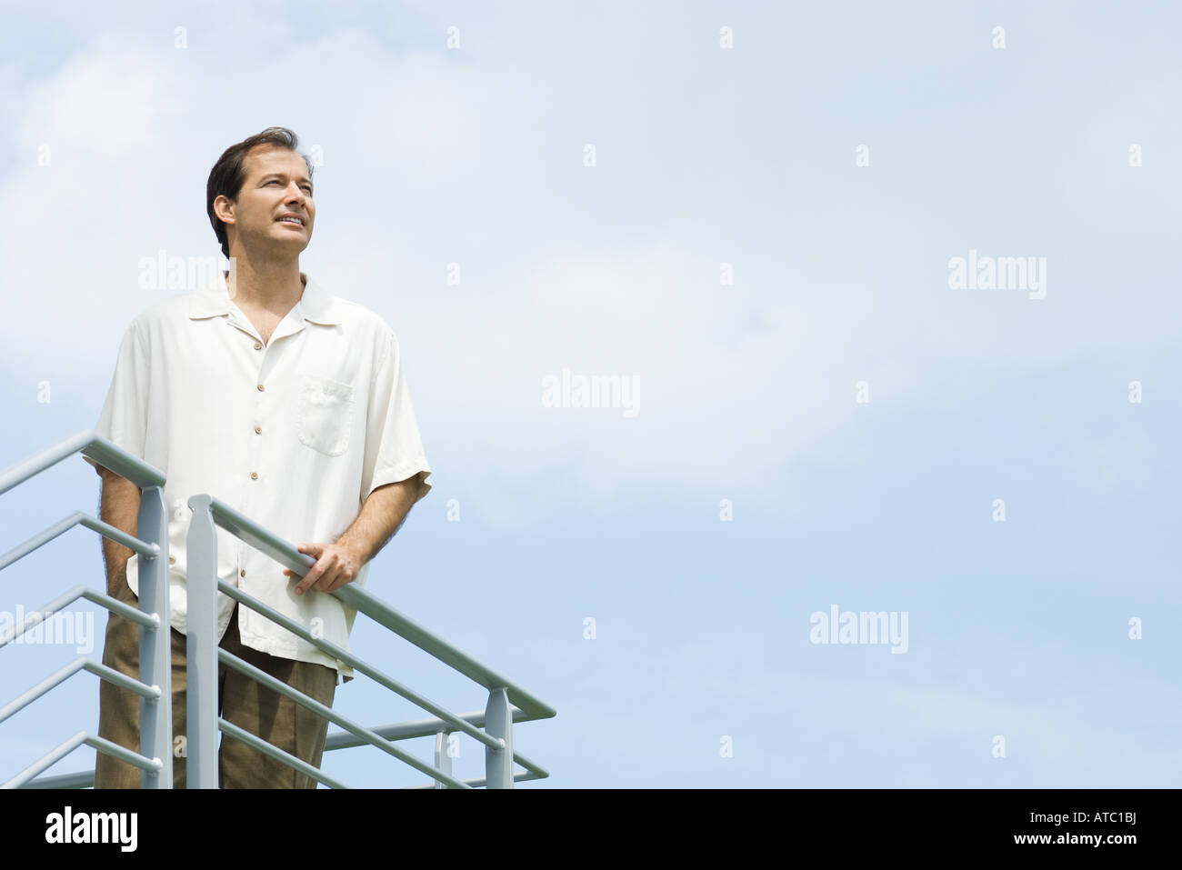 Man standing on balcony, looking away, smiling Stock Photo - Alamy