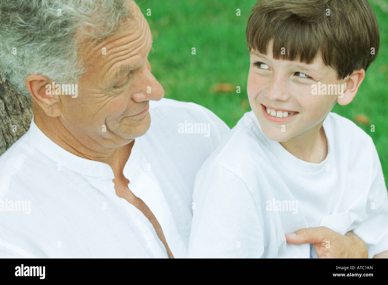 Grandfather and grandson smiling at each other, portrait Stock Photo ...
