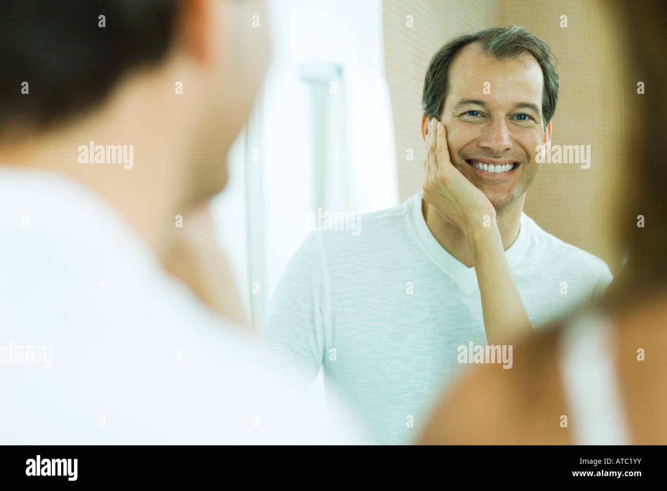 Man with wife's hand on his cheek, smiling at reflection in mirror ...
