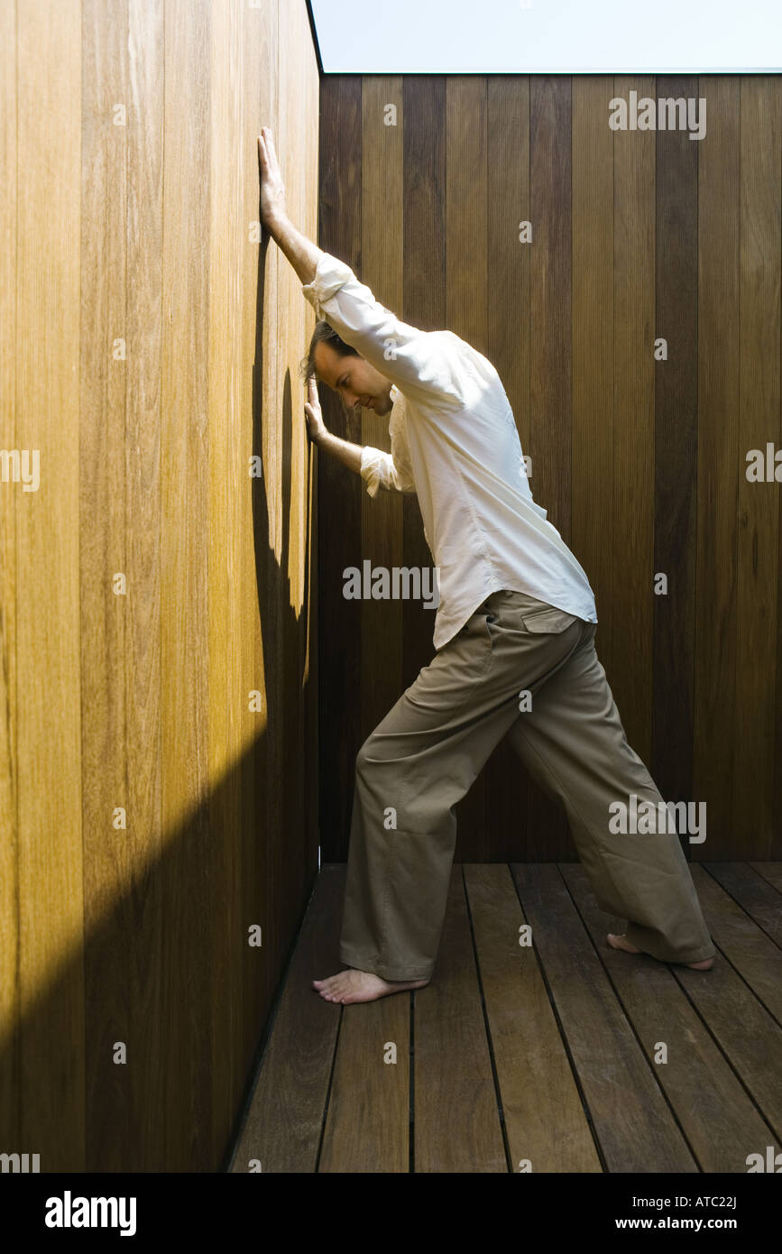 Man leaning against wall, arms raised, side view Stock Photo - Alamy