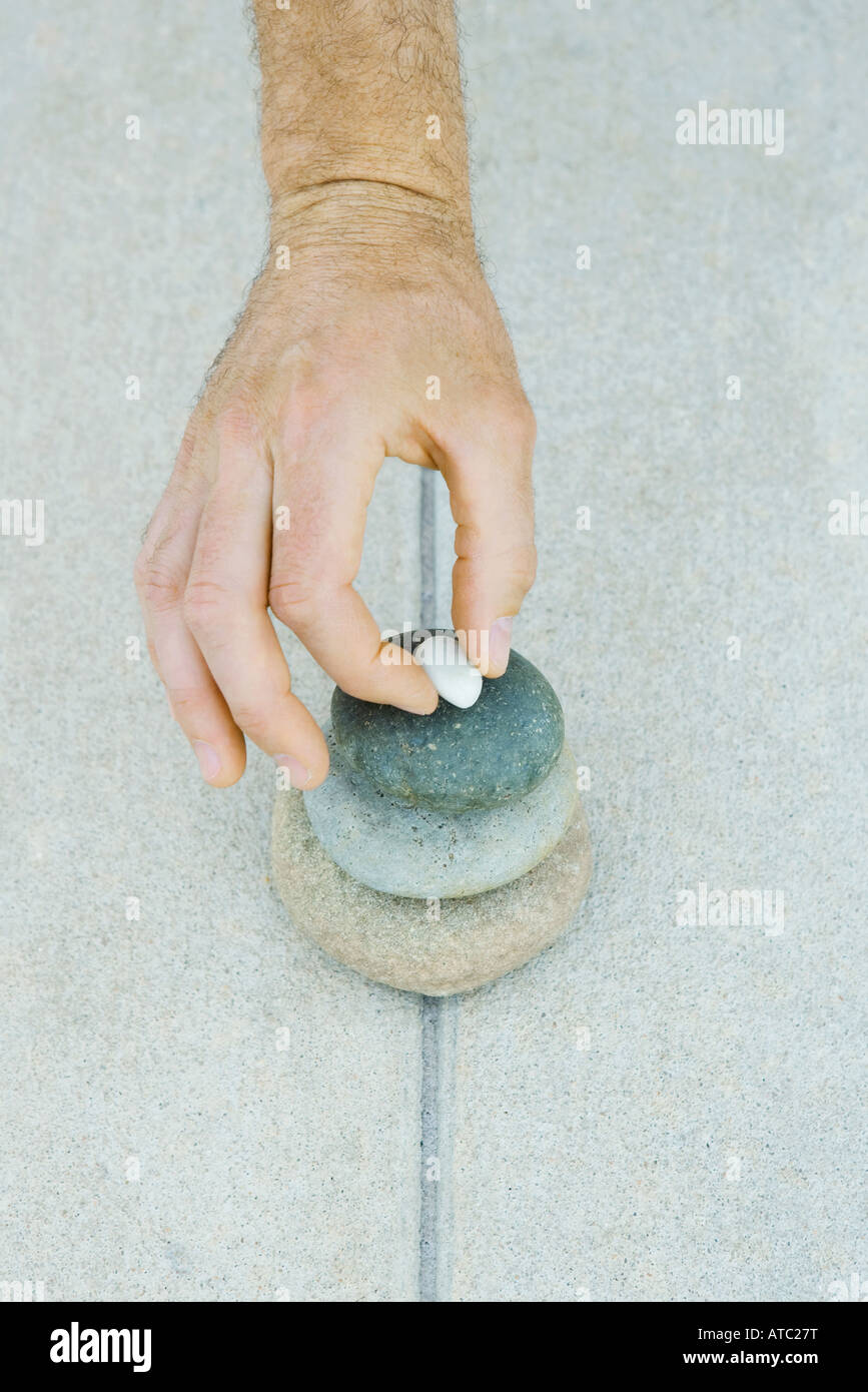 Man stacking pebbles, cropped view of hand Stock Photo - Alamy