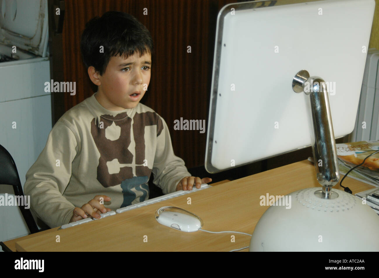 Model Released portrait of a seven year old boy playing with a dedsktop ...