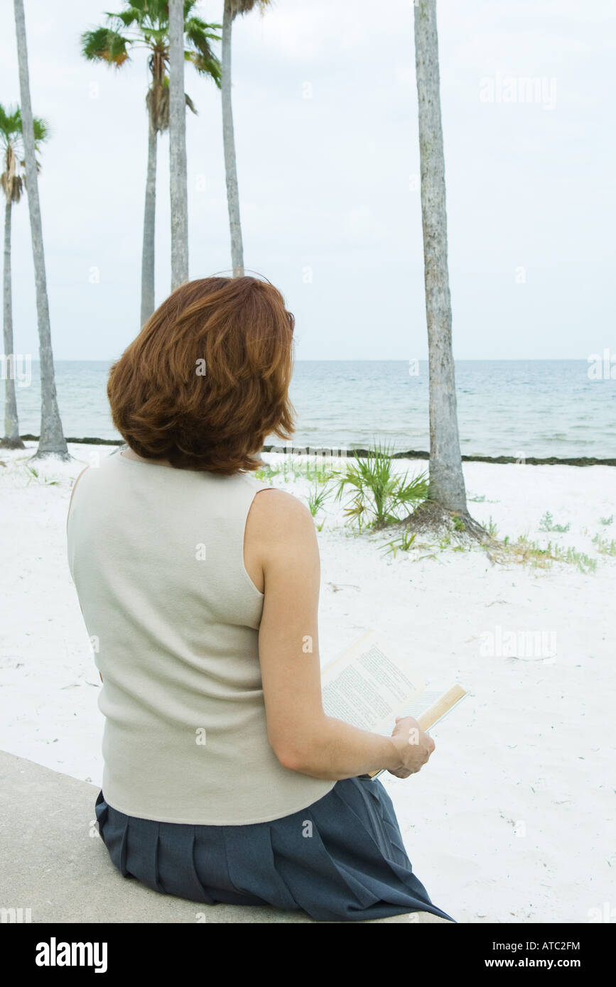 Woman reading book at the beach, rear view Stock Photo - Alamy