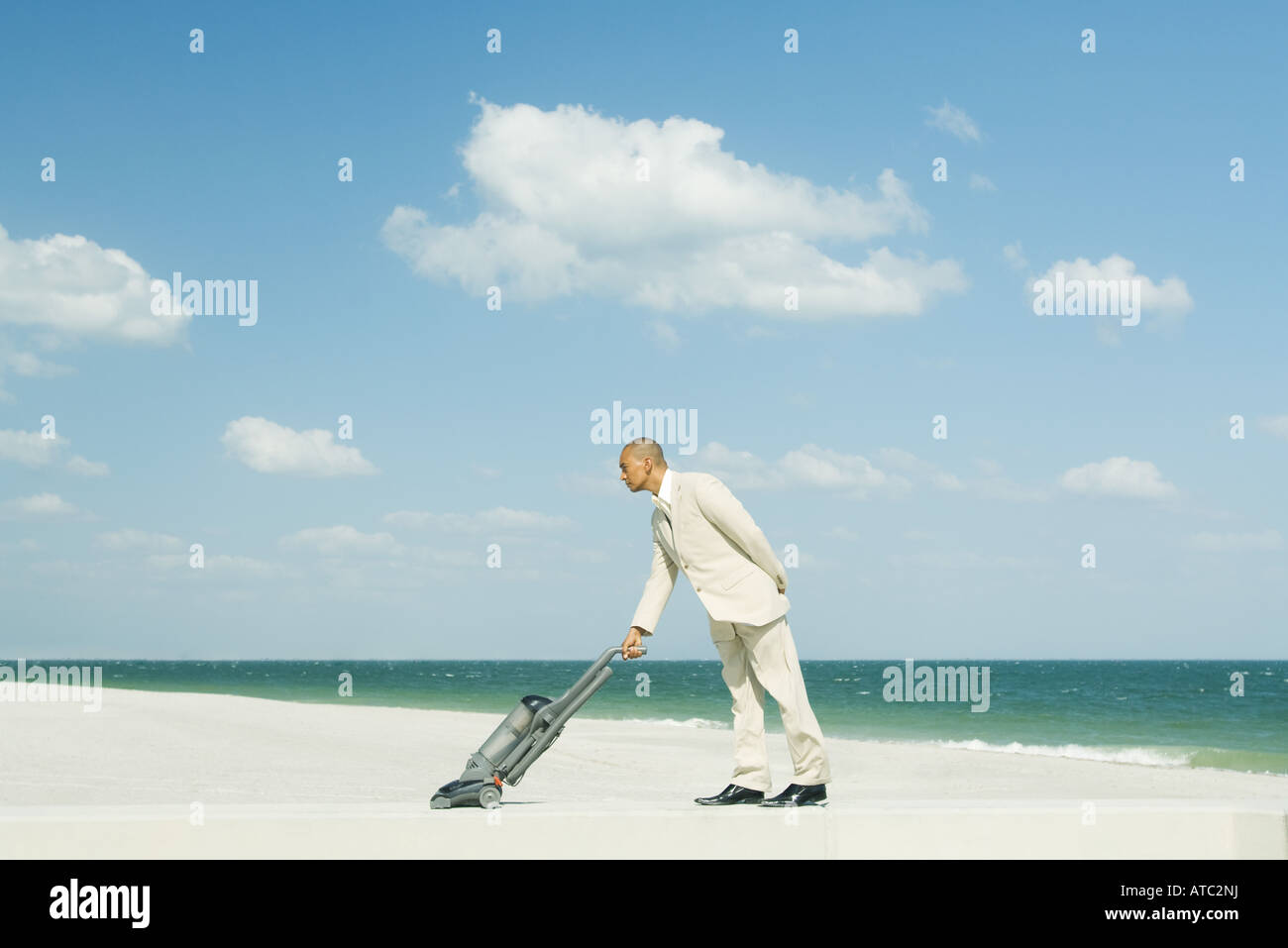 Man in suit using vacuum cleaner on beach, full length Stock Photo - Alamy