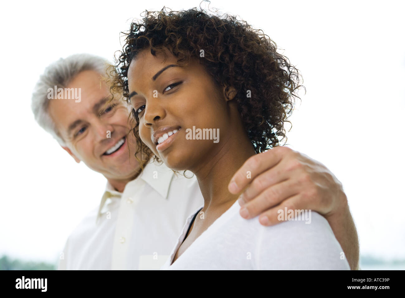 Man with arm around woman's shoulder, woman smiling at camera, side ...