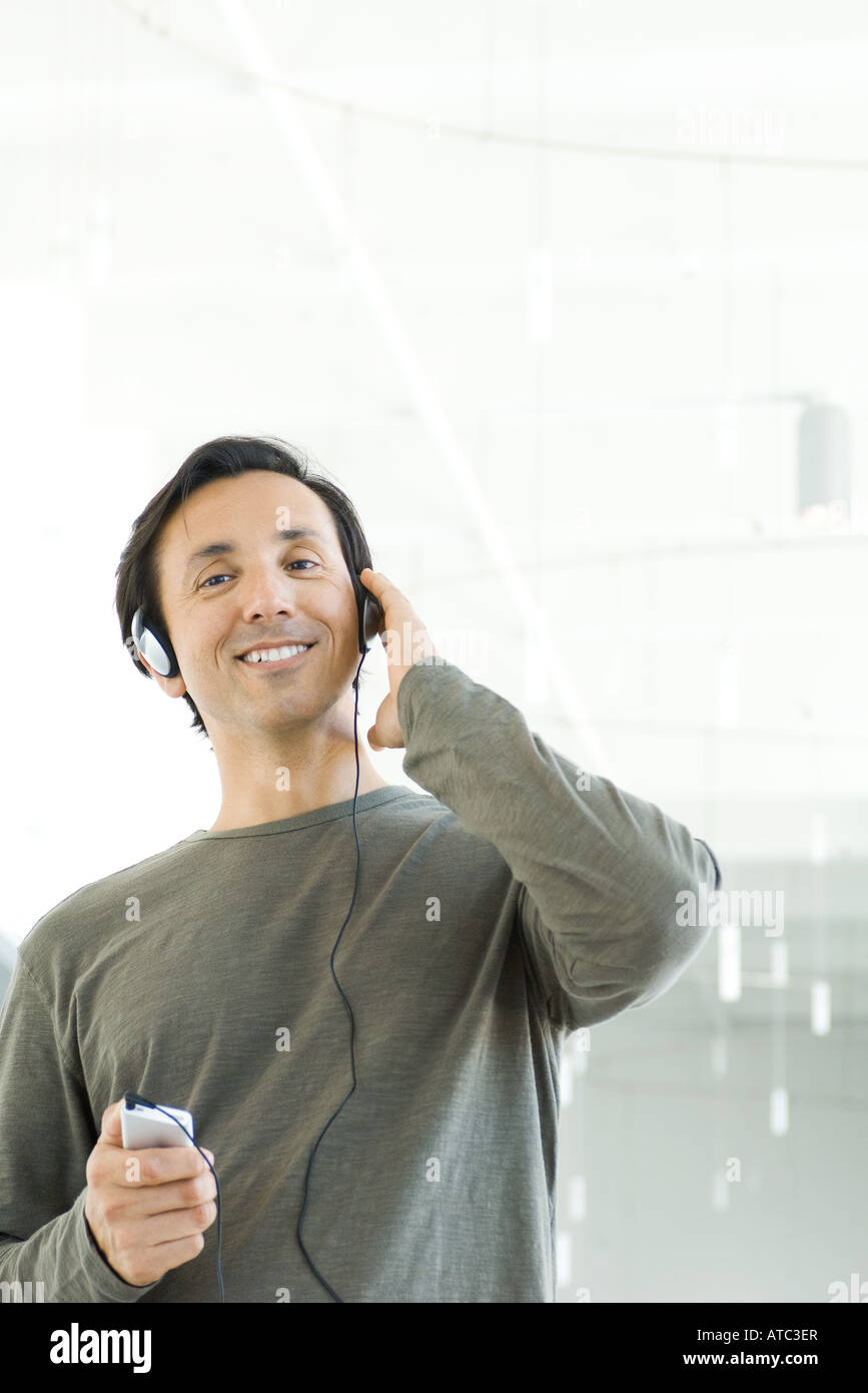 Man listening to mp3 player, hand raised, smiling at camera Stock Photo ...