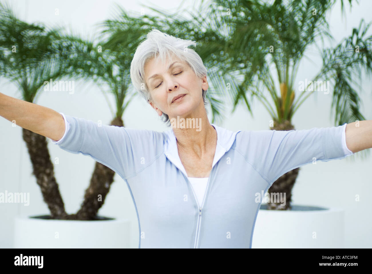 Senior woman with arms outstretched, head tilted, eyes closed Stock ...