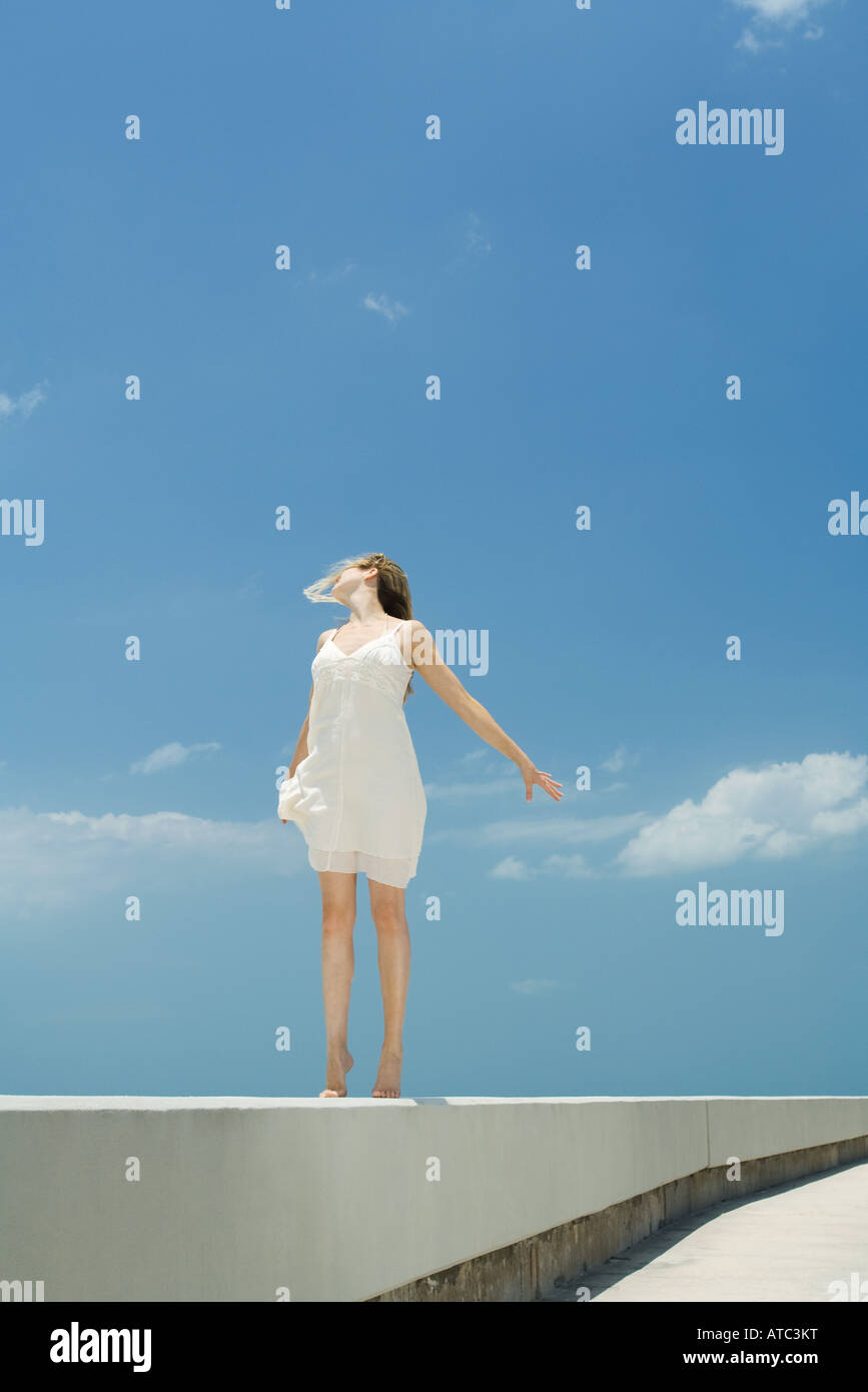 Young woman standing on tiptoe on low wall, arms out, head back Stock ...