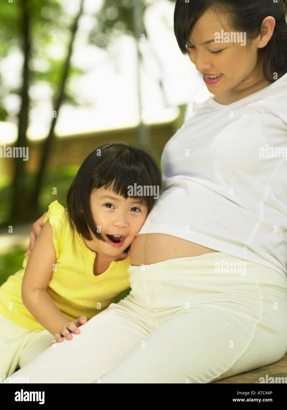 girl putting her ear close to mums tummy Stock Photo - Alamy