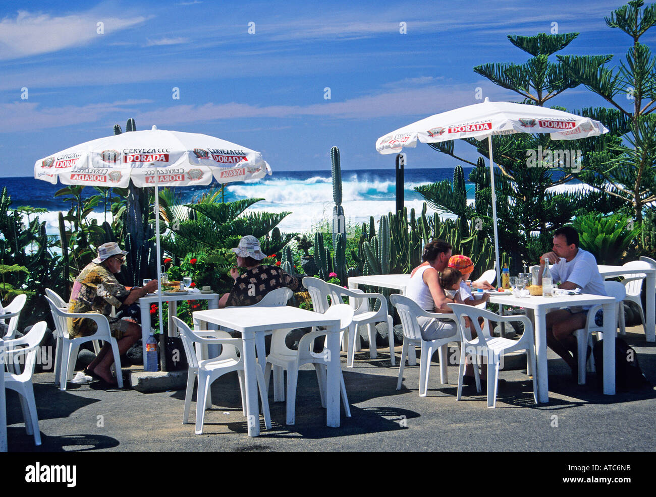 People enjoy a light meal and a break from the sun under sun shades at ...