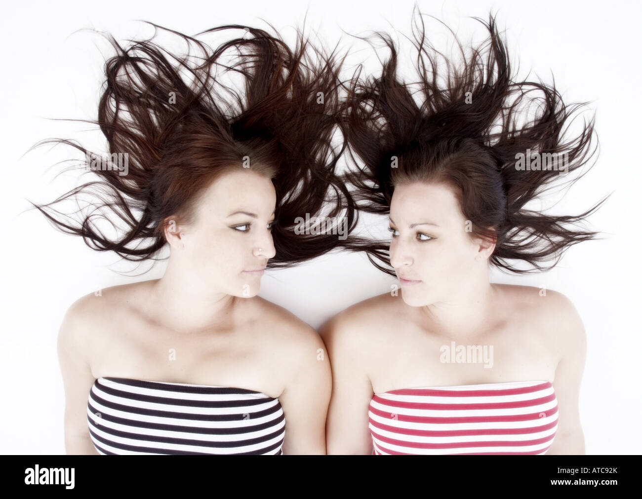 twin sisters in striped tops, lying side by side Stock Photo - Alamy