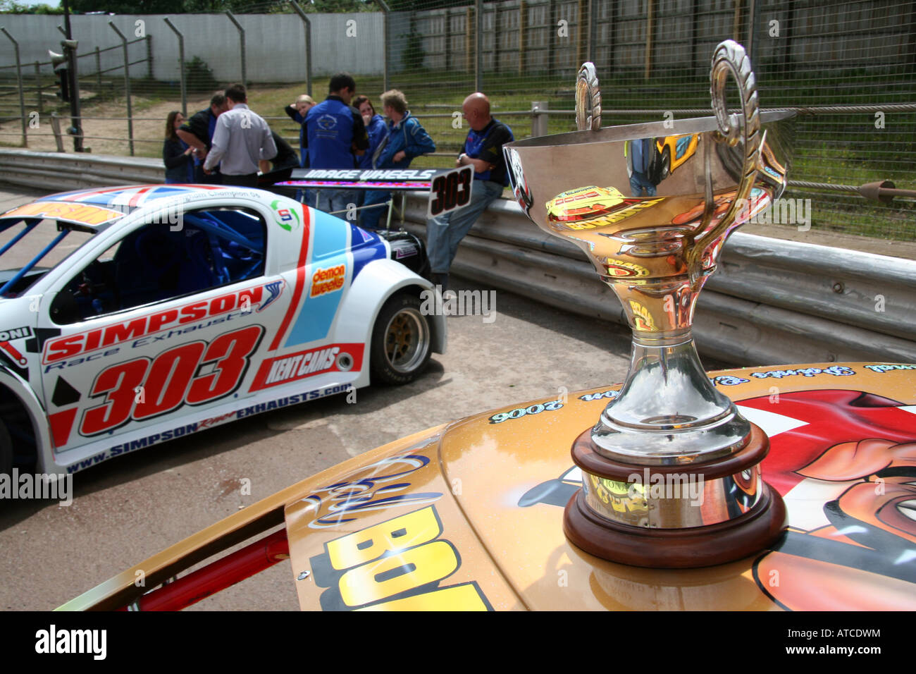 Close up of a winner's cup on a hot rod racing car with another race ...