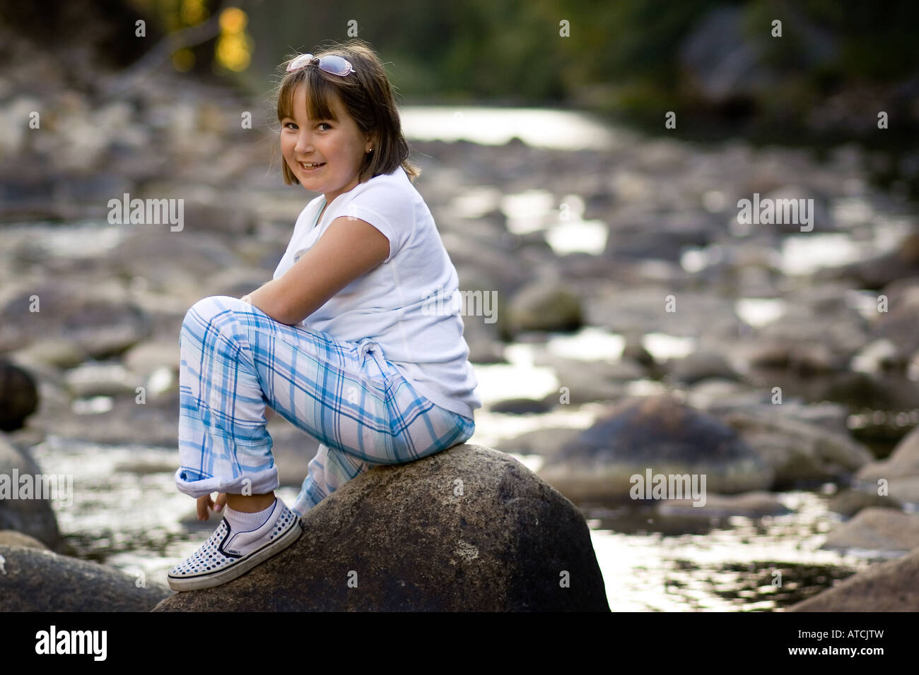 A young girl sits on rocks in the Merced River in Yosemite National ...