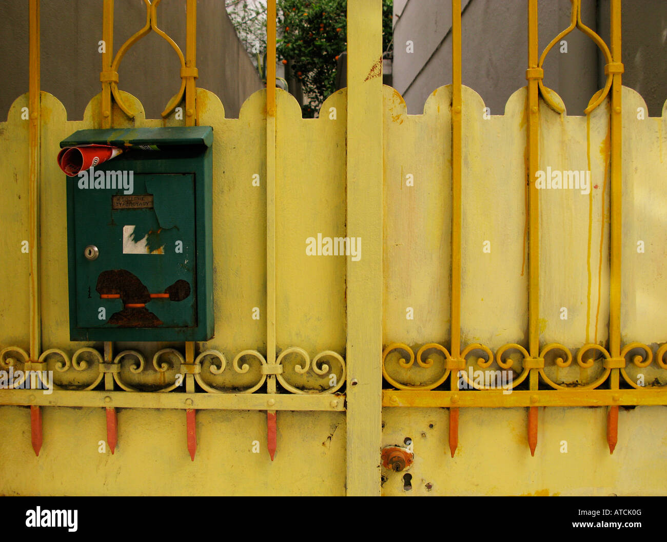 Old greek letter box against an old yellow gate with mandarin tree in ...