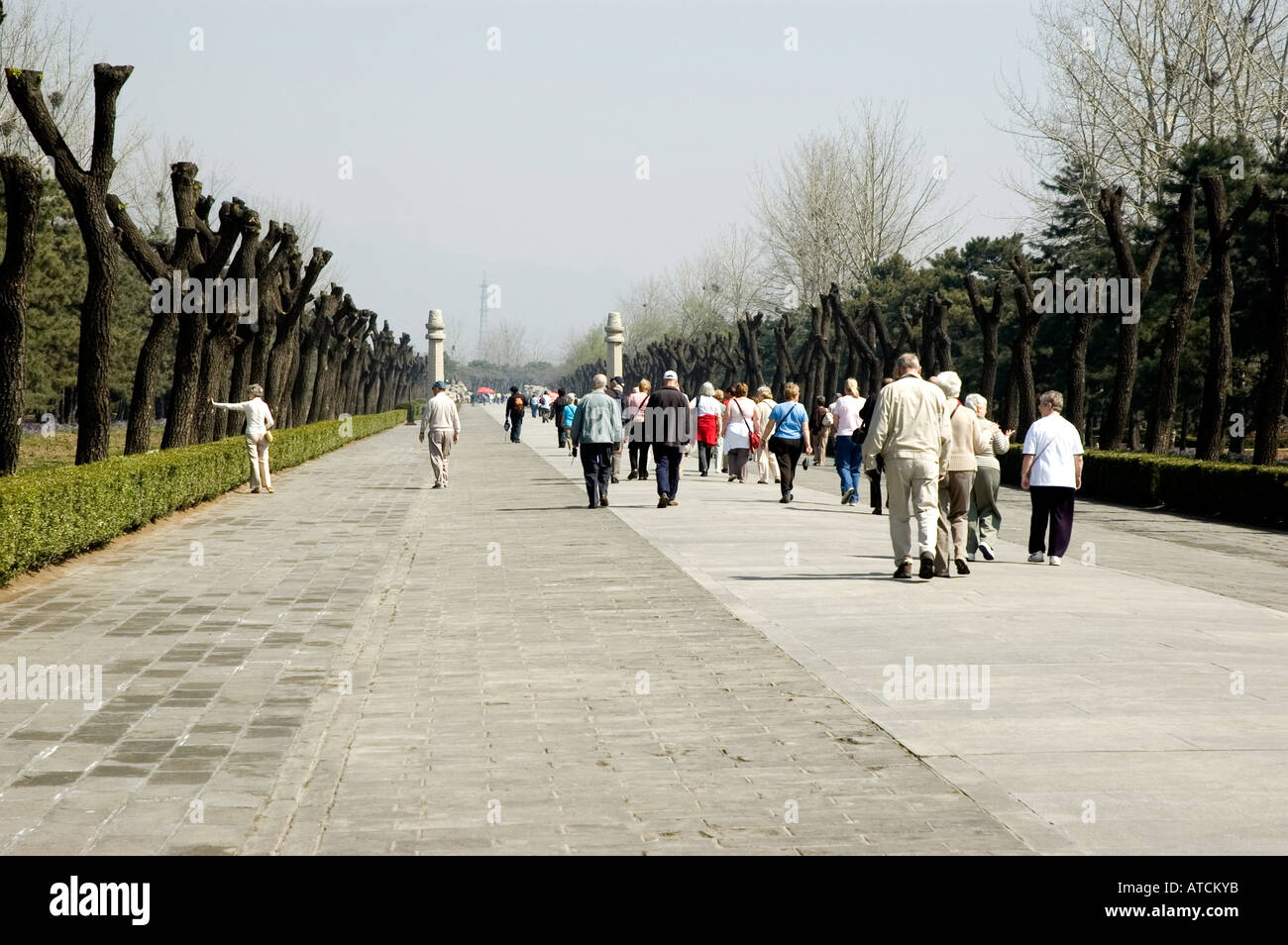 Tourists walking along the Sacred Way towards two hexagonal columns ...
