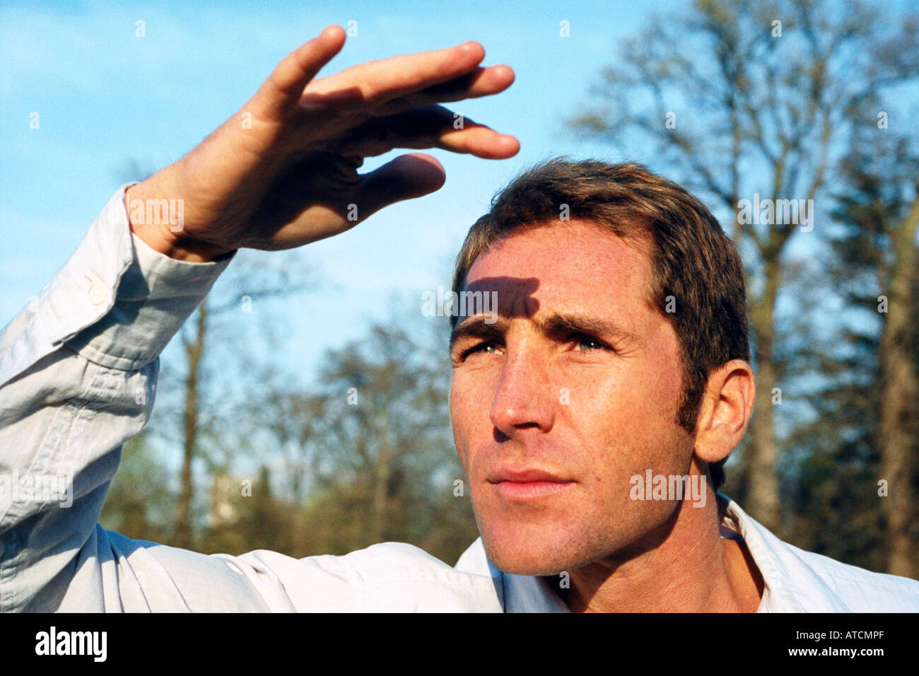 Man looking into distance, hand protecting from sun Stock Photo - Alamy