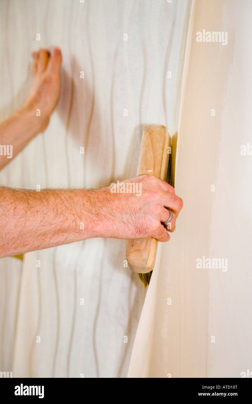 Person hanging wallpaper using decorator s paper hanging brush to ...