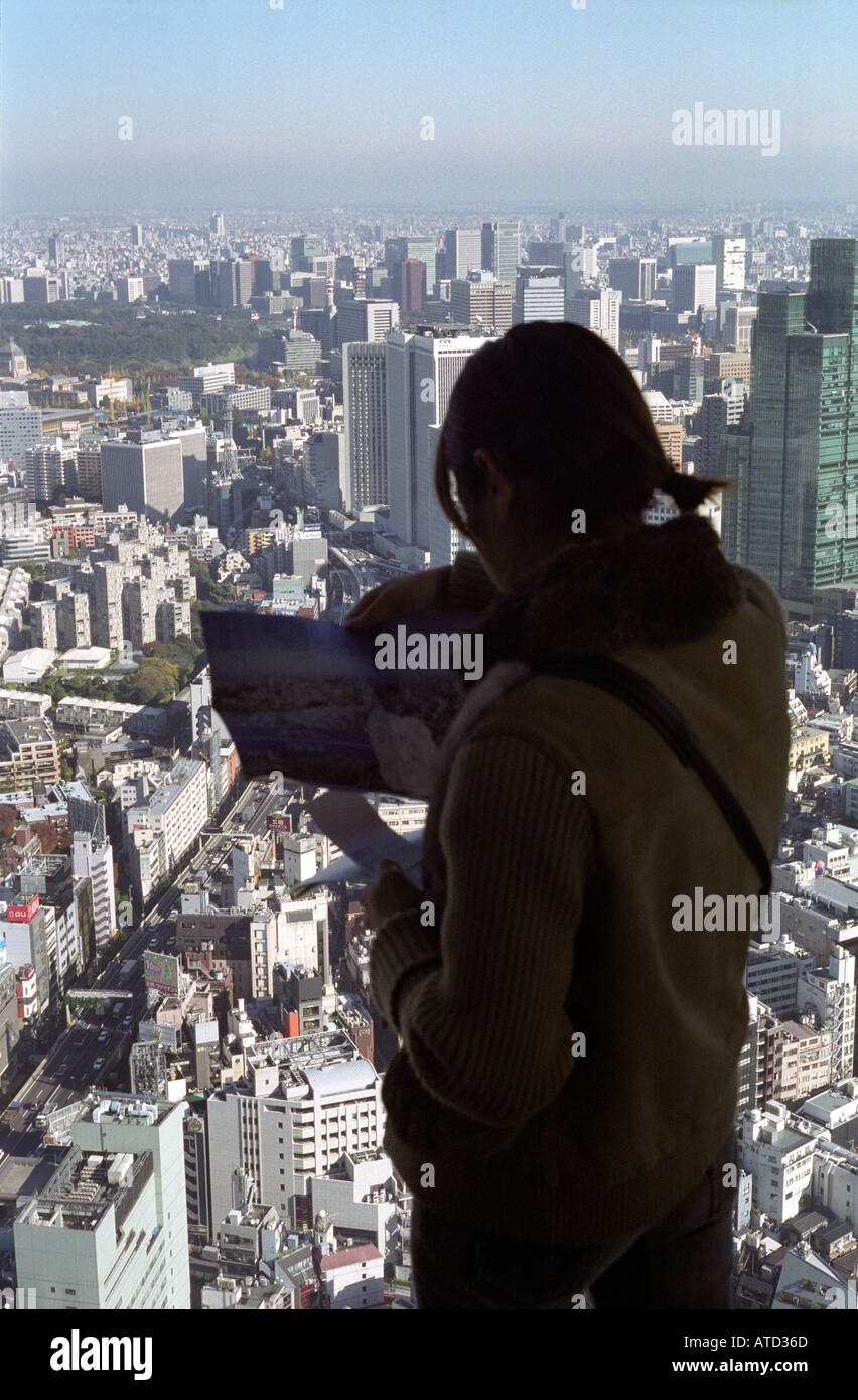 A tourist uses a map to identify the features of the Tokyo landscape as ...