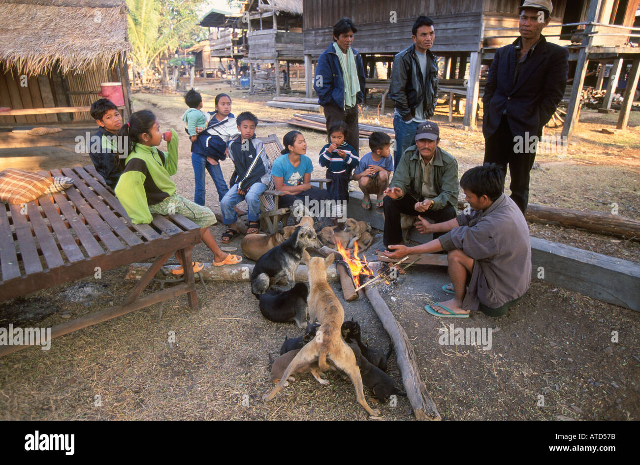 People and dogs watching meat being cooked over fire in remote village ...