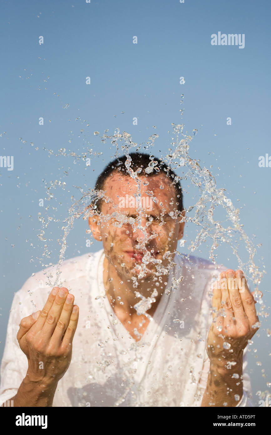 Man splashing water on himself against a blue sky in India Stock Photo ...