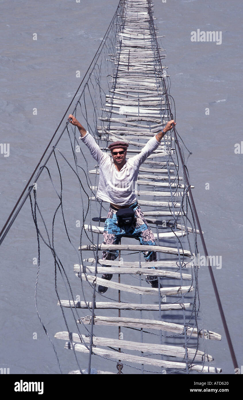 Intrepid traveller crossing the Hunza river on suspended footbridge ...