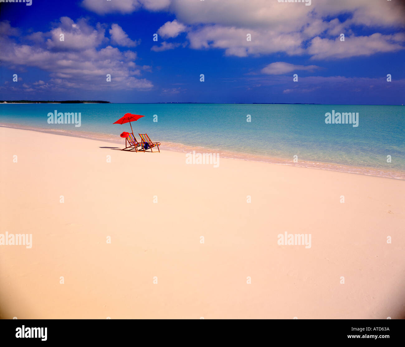 Tropical scene of two colorful beach chairs and an umbrella sitting at ...
