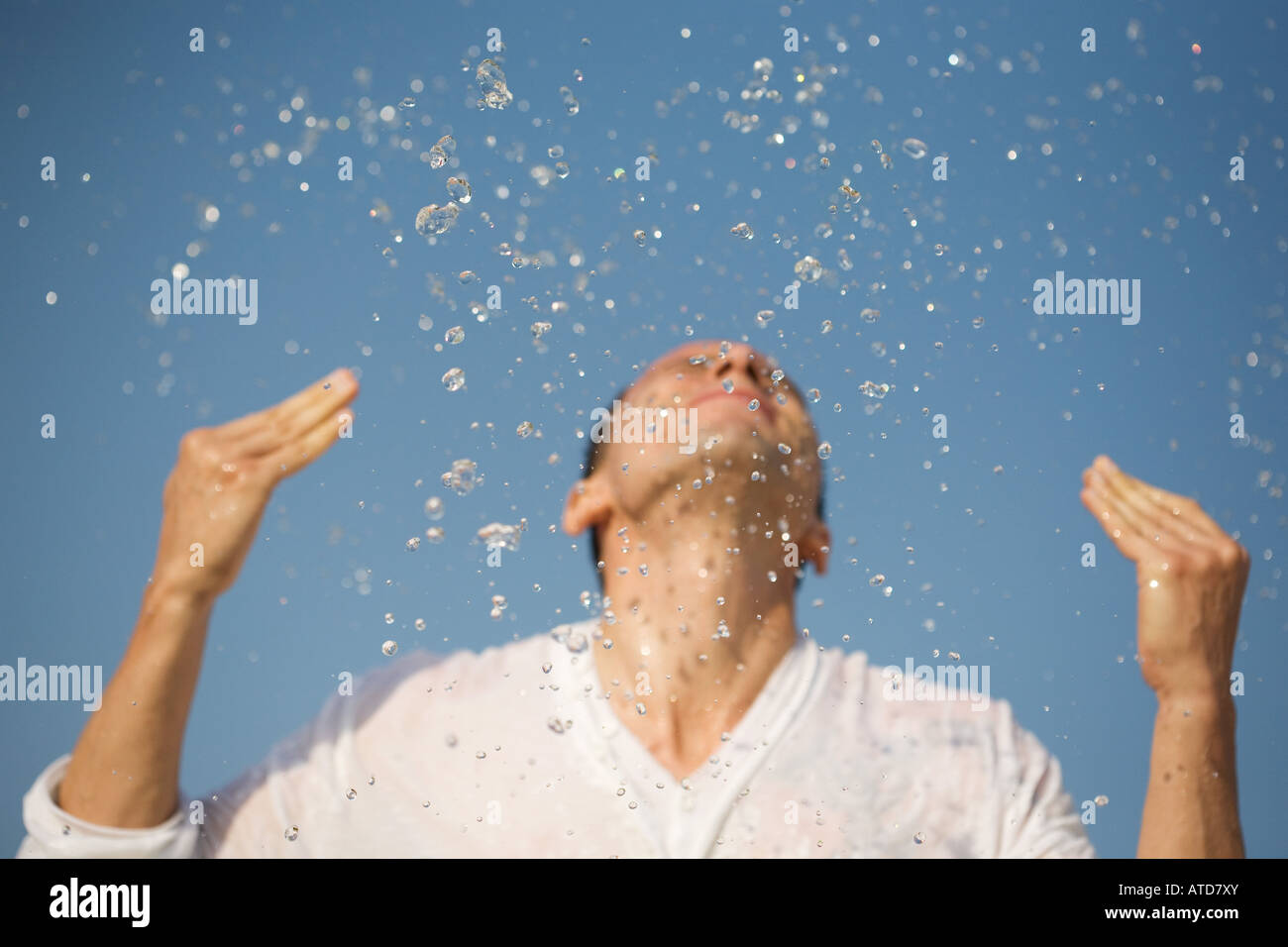 Man splashing water on himself against a blue sky in India Stock Photo ...