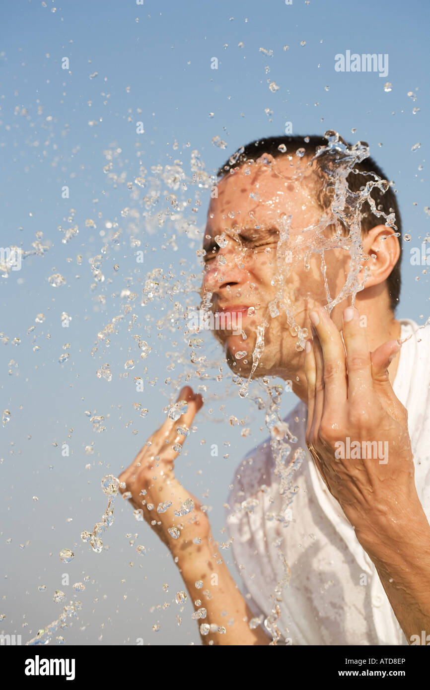 Man splashing water on himself against a blue sky in India Stock Photo ...