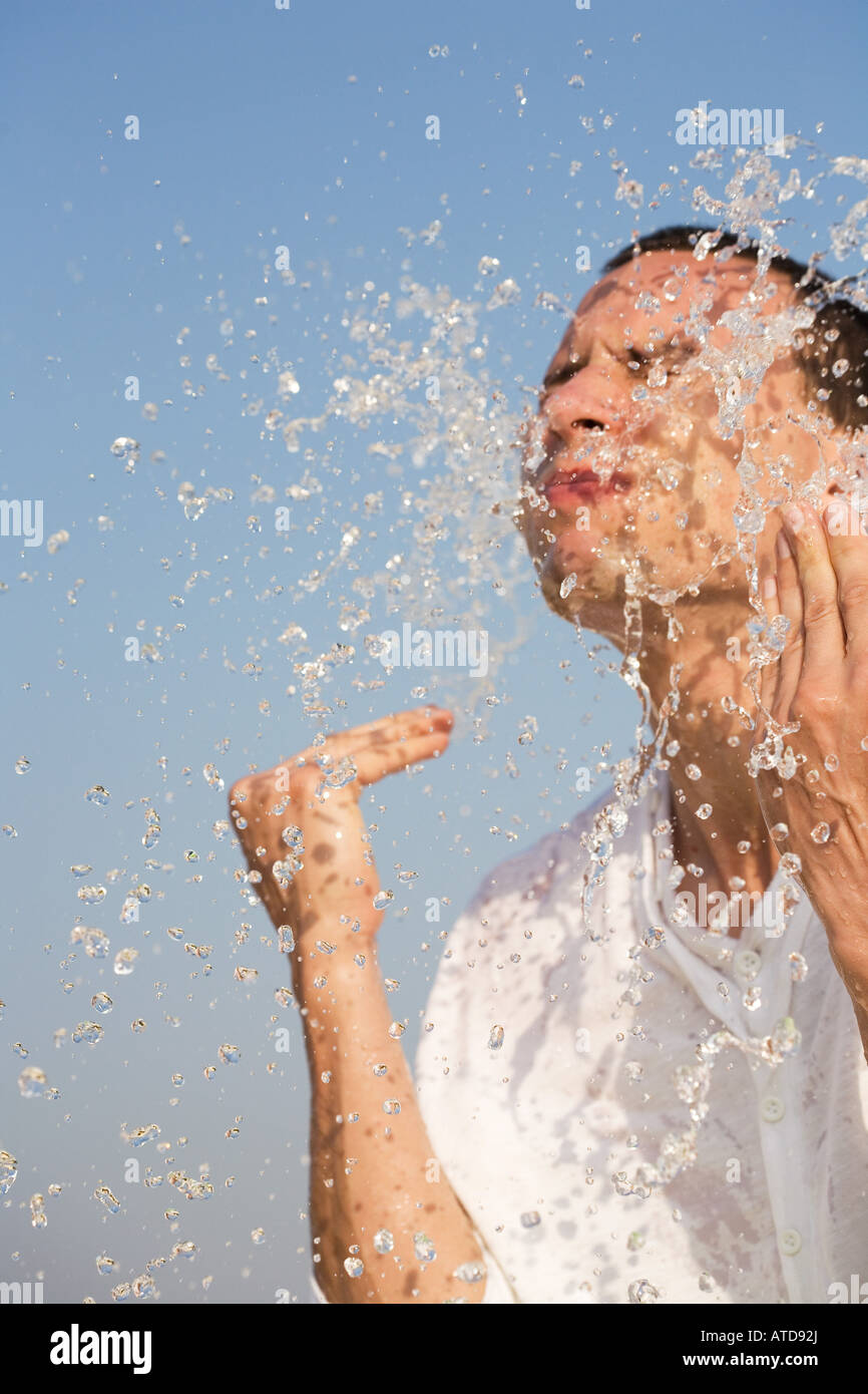 Man splashing water on himself against a blue sky in India Stock Photo ...