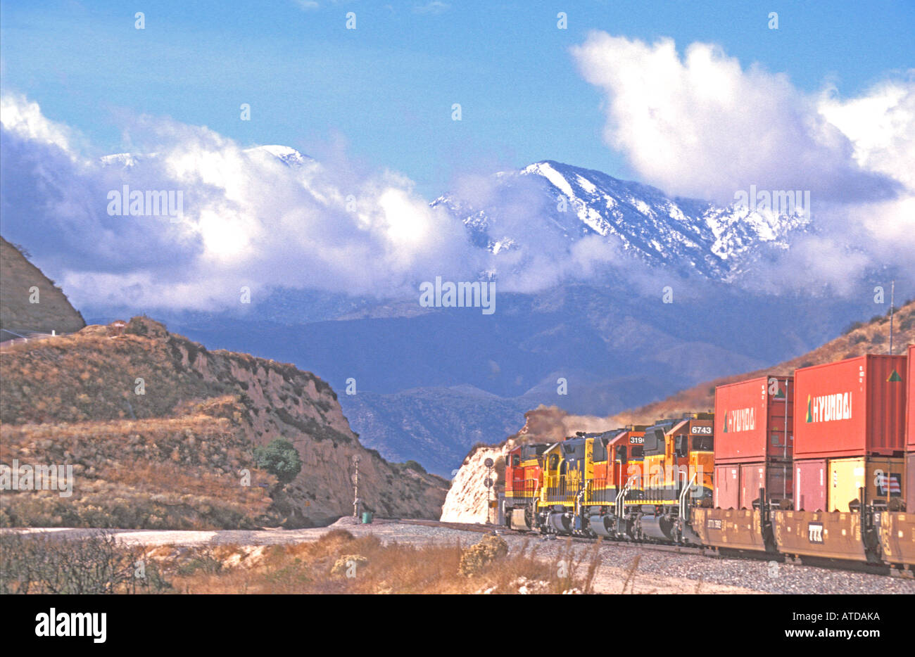 Four BNSF engines hauling a train of shipping containers starts down ...
