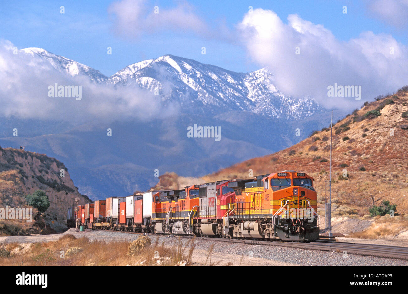 Four BNSF engines with a train of full roll on roll off shipping containers and their trailers ...