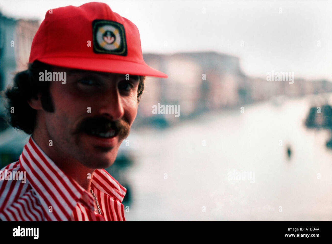 Man wearing a sriped shirt and baseball cap both red smiling at the ...