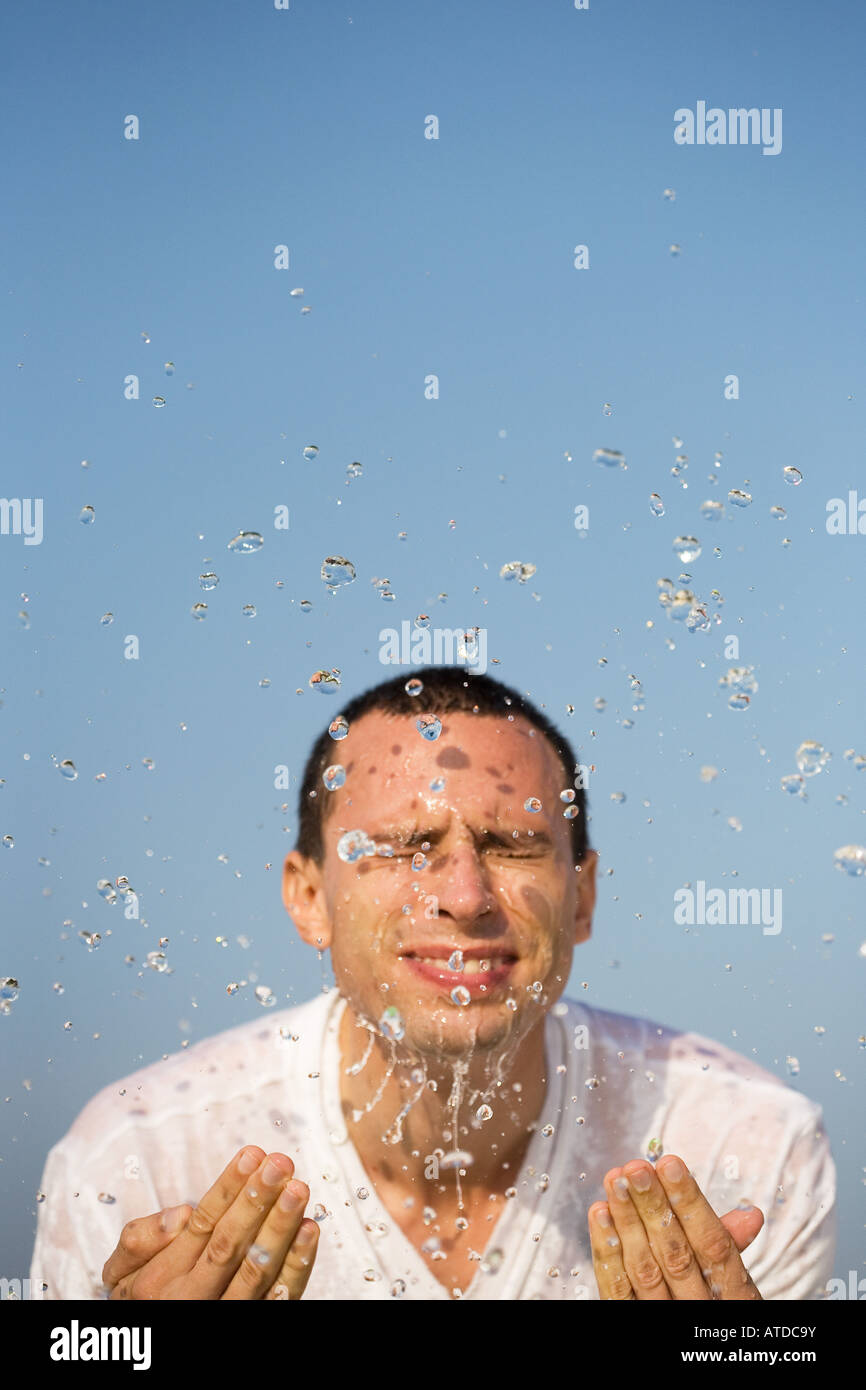 Man splashing water on himself against a blue sky in India Stock Photo ...