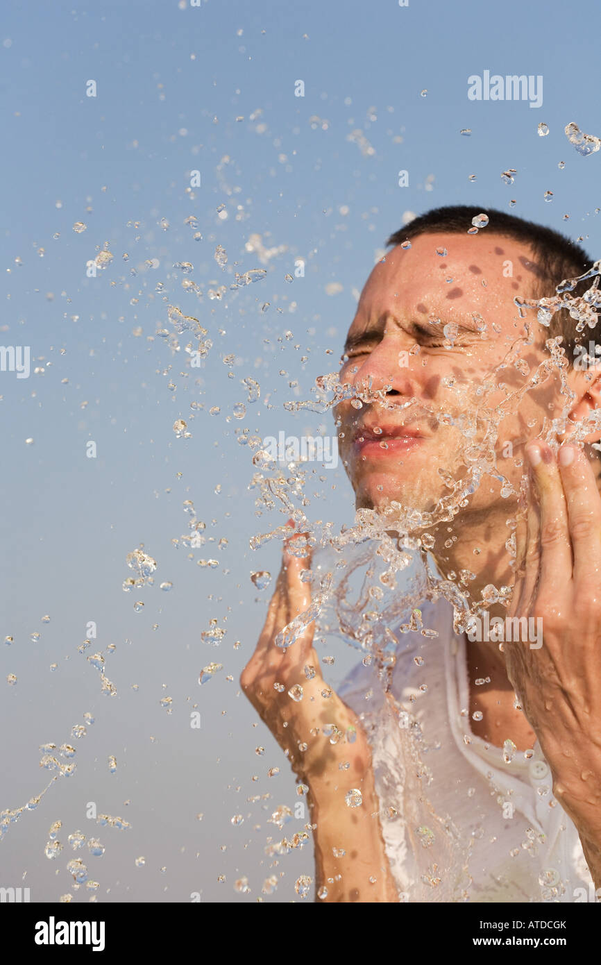 Man splashing water on himself against a blue sky in India Stock Photo ...