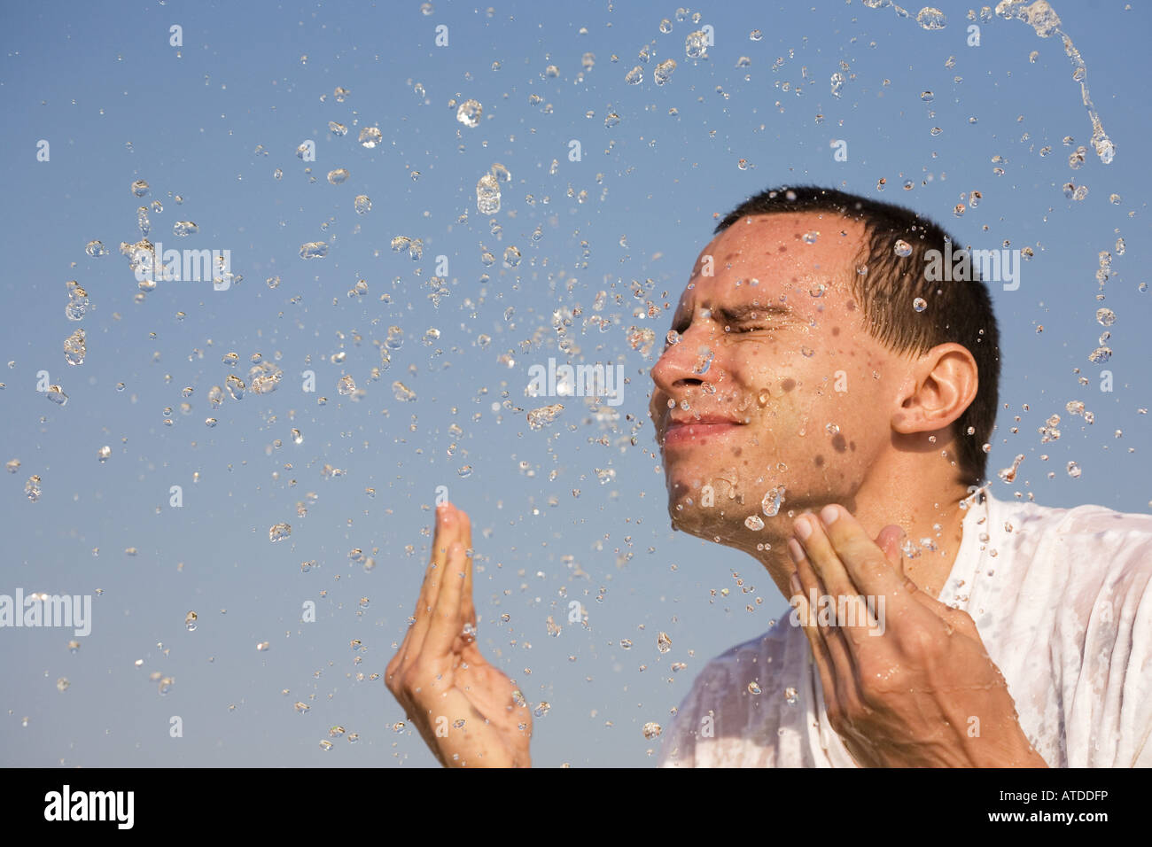 Man splashing water on himself against a blue sky in India Stock Photo ...