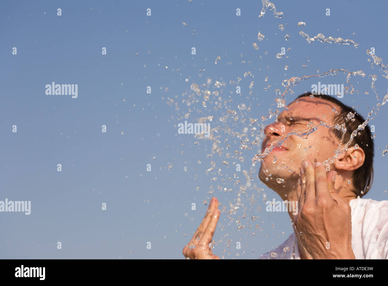 Man splashing water on himself against a blue sky in India Stock Photo ...