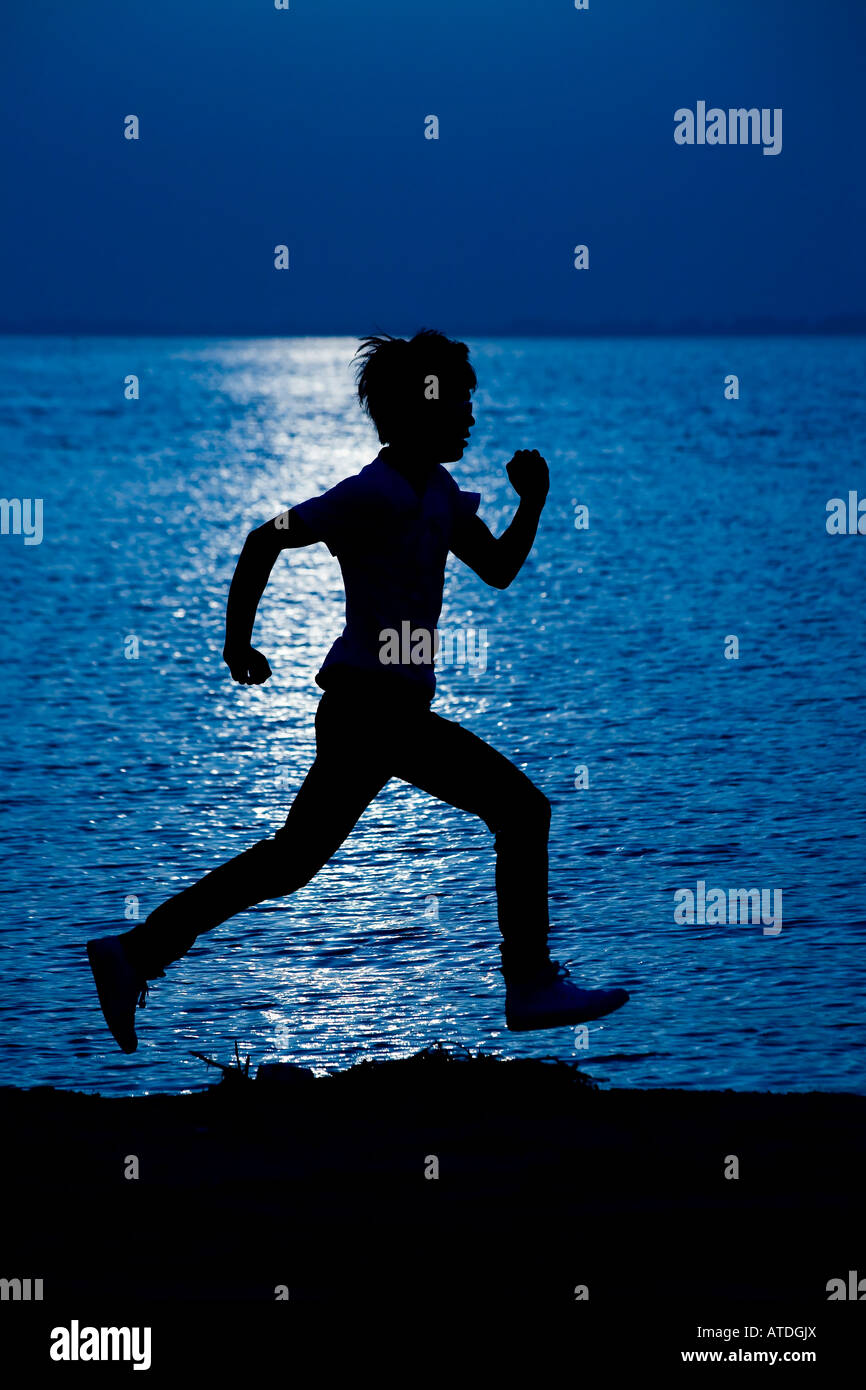 Silhouette of young man running by lake Stock Photo - Alamy
