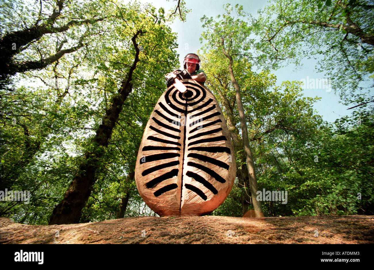 Recycled wood turned into sculpture by man in hard hat with chainsaw ...