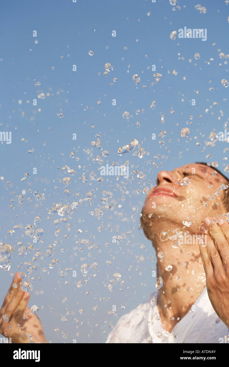 Man splashing water on himself against a blue sky in India Stock Photo ...