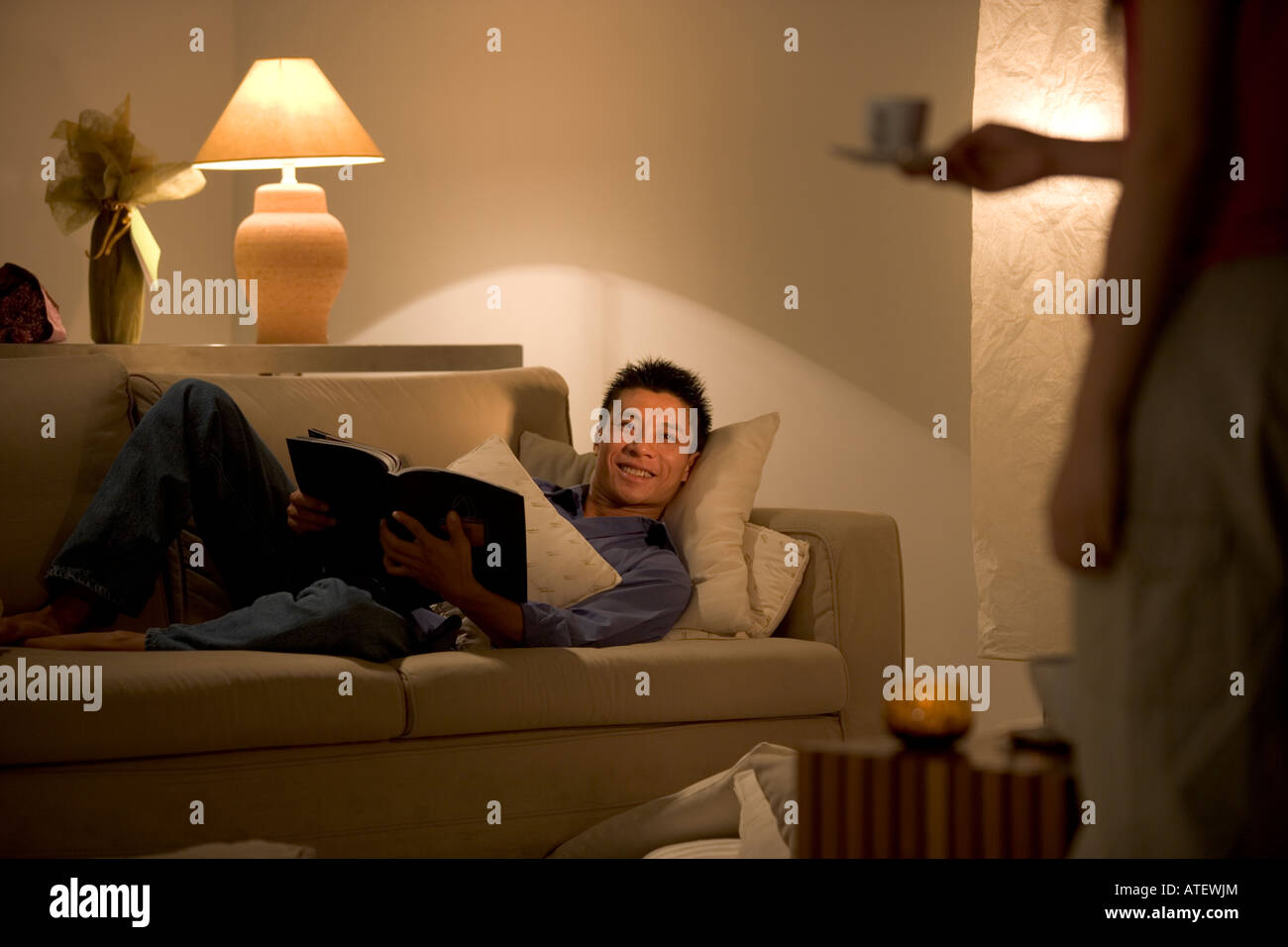 Young man lying on a couch smiling Stock Photo - Alamy