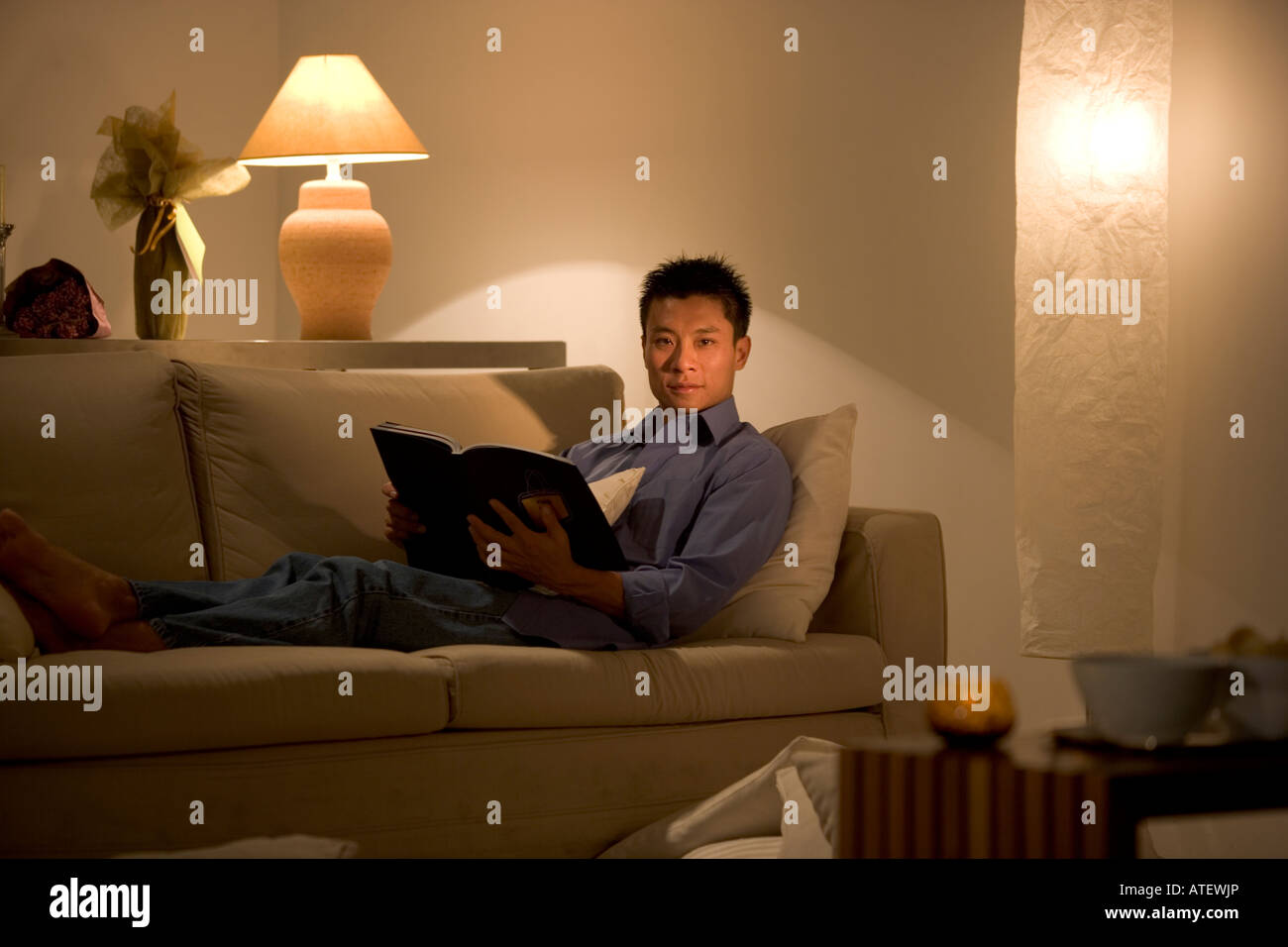 Portrait of a young man reclining on a couch Stock Photo - Alamy