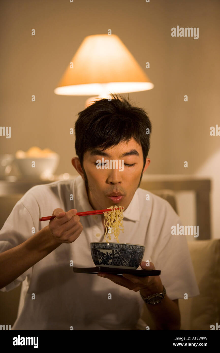Young man eating noodles Stock Photo - Alamy