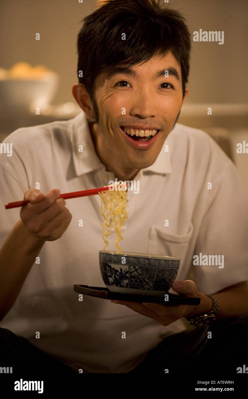 Young man eating noodles Stock Photo - Alamy