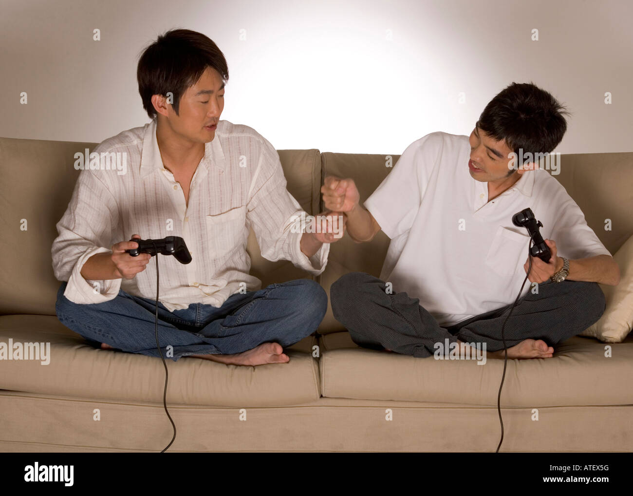 Two young men sitting on a couch playing video games Stock Photo - Alamy
