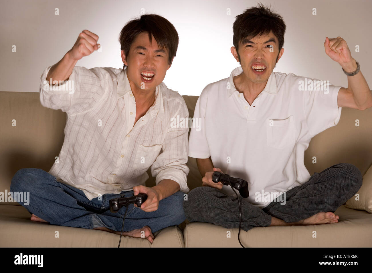 Two young men sitting on a couch playing video games Stock Photo - Alamy