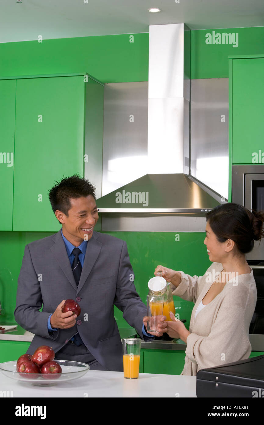 Young woman serving juice to a young man in the kitchen Stock Photo - Alamy