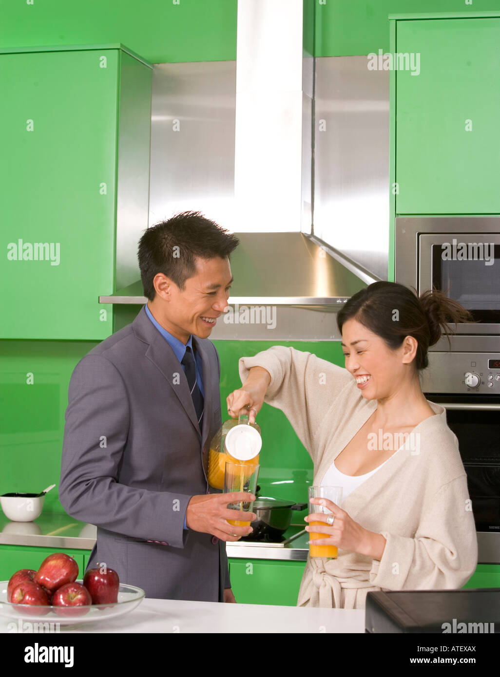 Young woman serving juice to a young man in the kitchen Stock Photo - Alamy